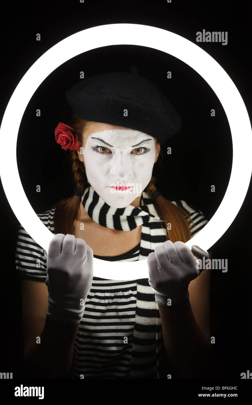 Portrait of a young lady dressed up as a mime isolated over black ...
