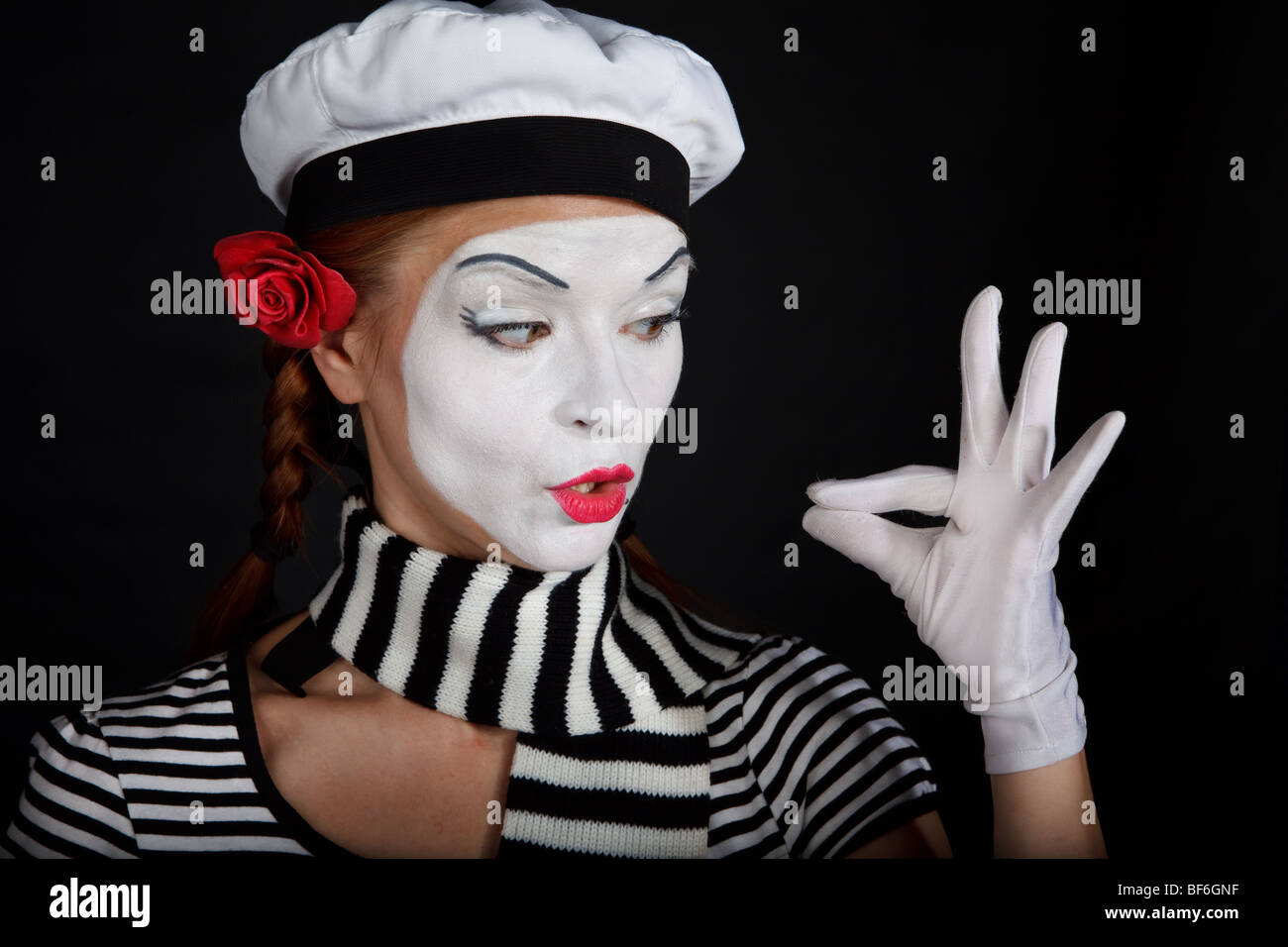 Portrait of a young lady dressed up as a mime isolated over black ...