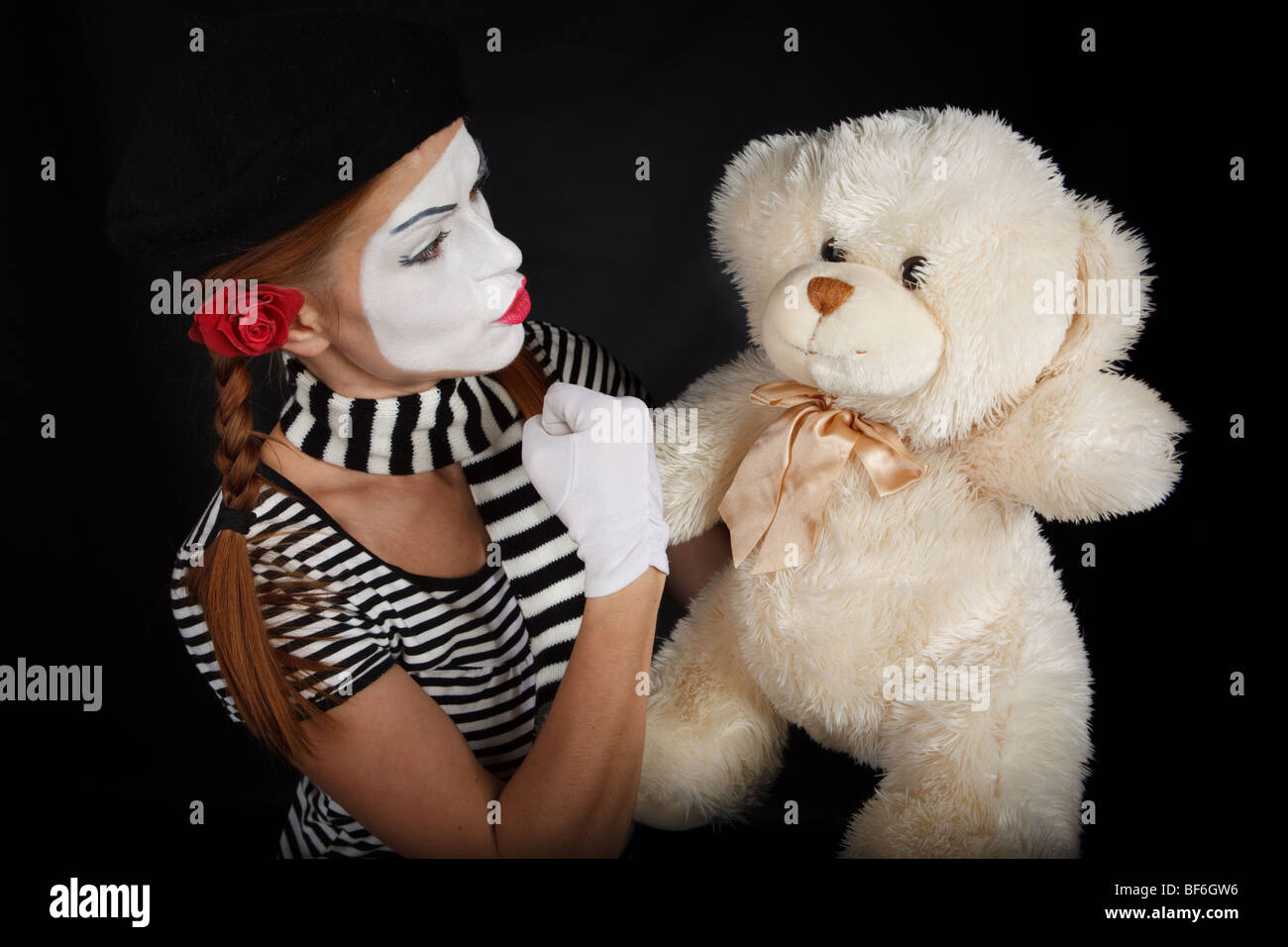 Portrait of a young lady dressed up as a mime isolated over black ...