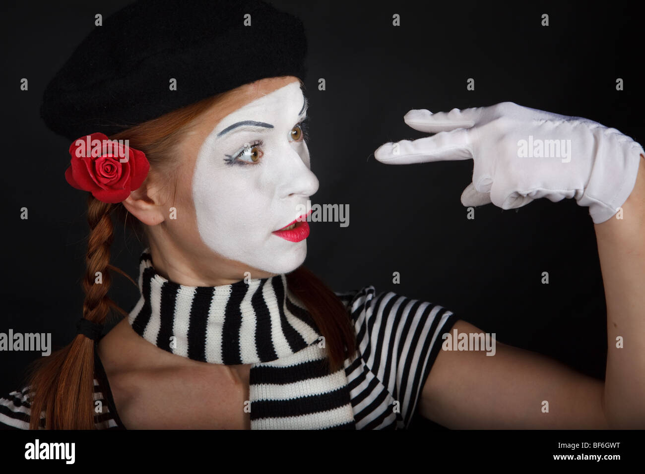 Portrait of a young lady dressed up as a mime isolated over black ...
