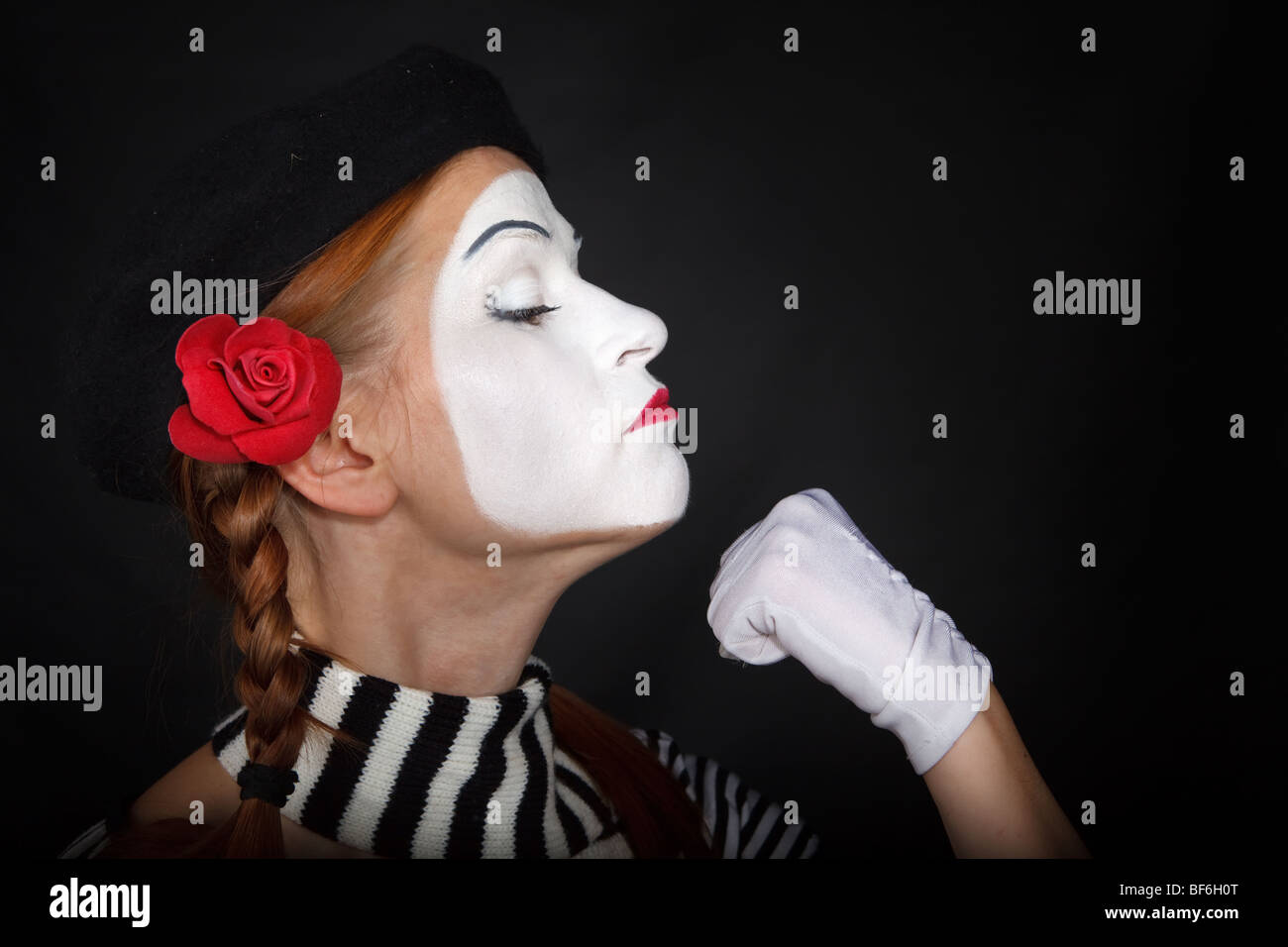 Portrait of a young lady dressed up as a mime isolated over black ...
