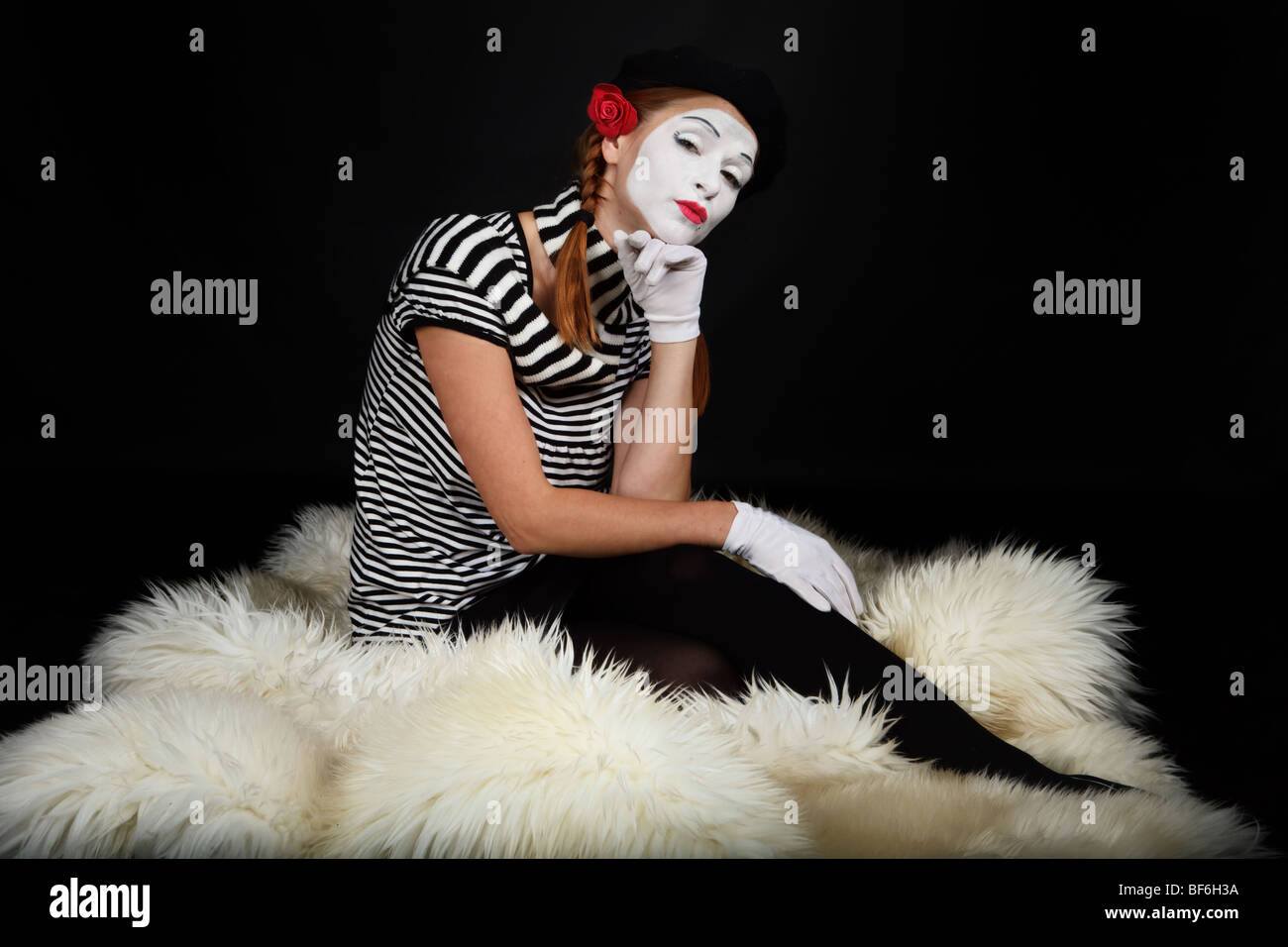 Portrait of a young lady dressed up as a mime isolated over black ...