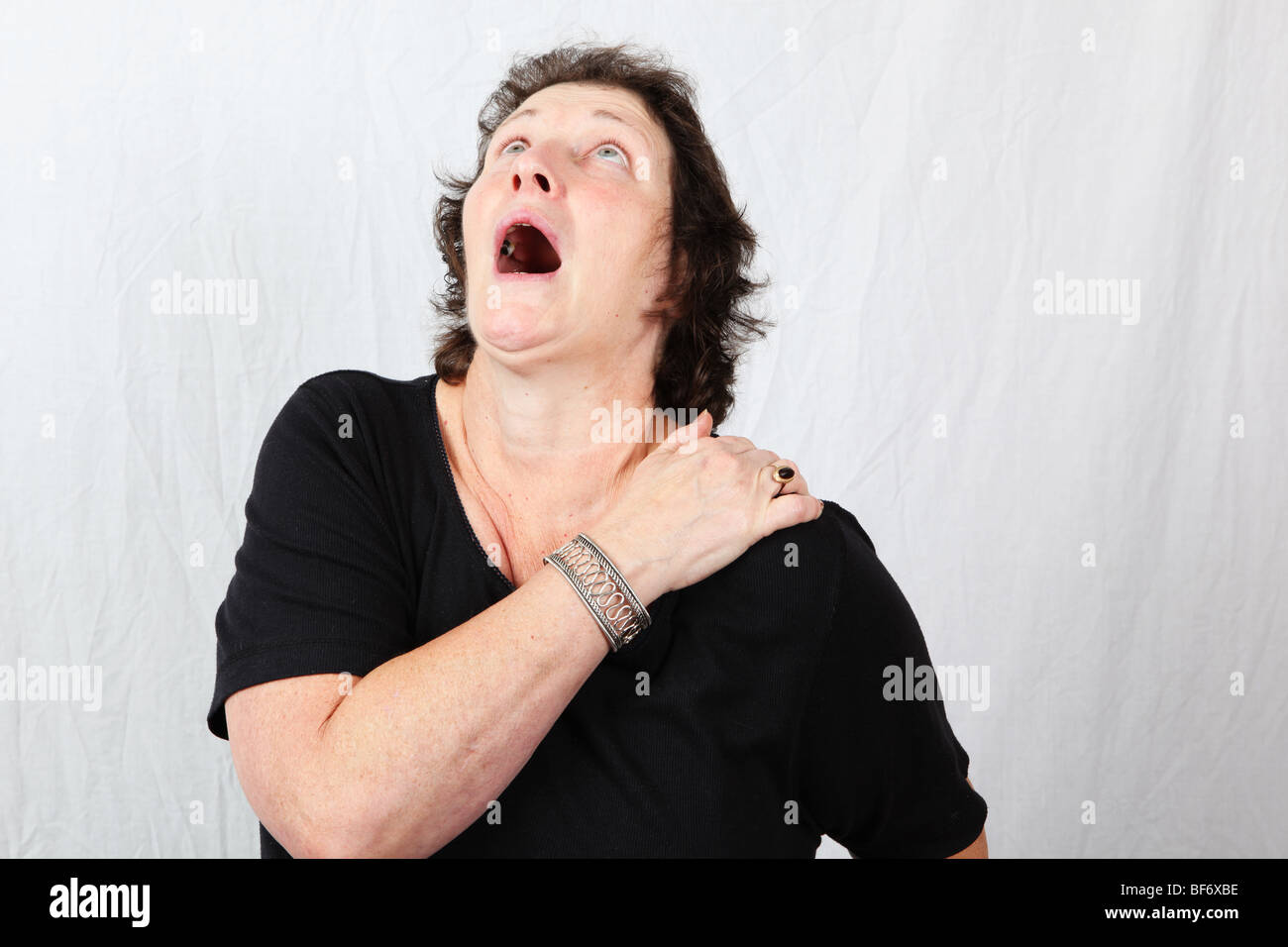 50s 60s woman holds shoulder with severe chronic arthritis joint pain ...