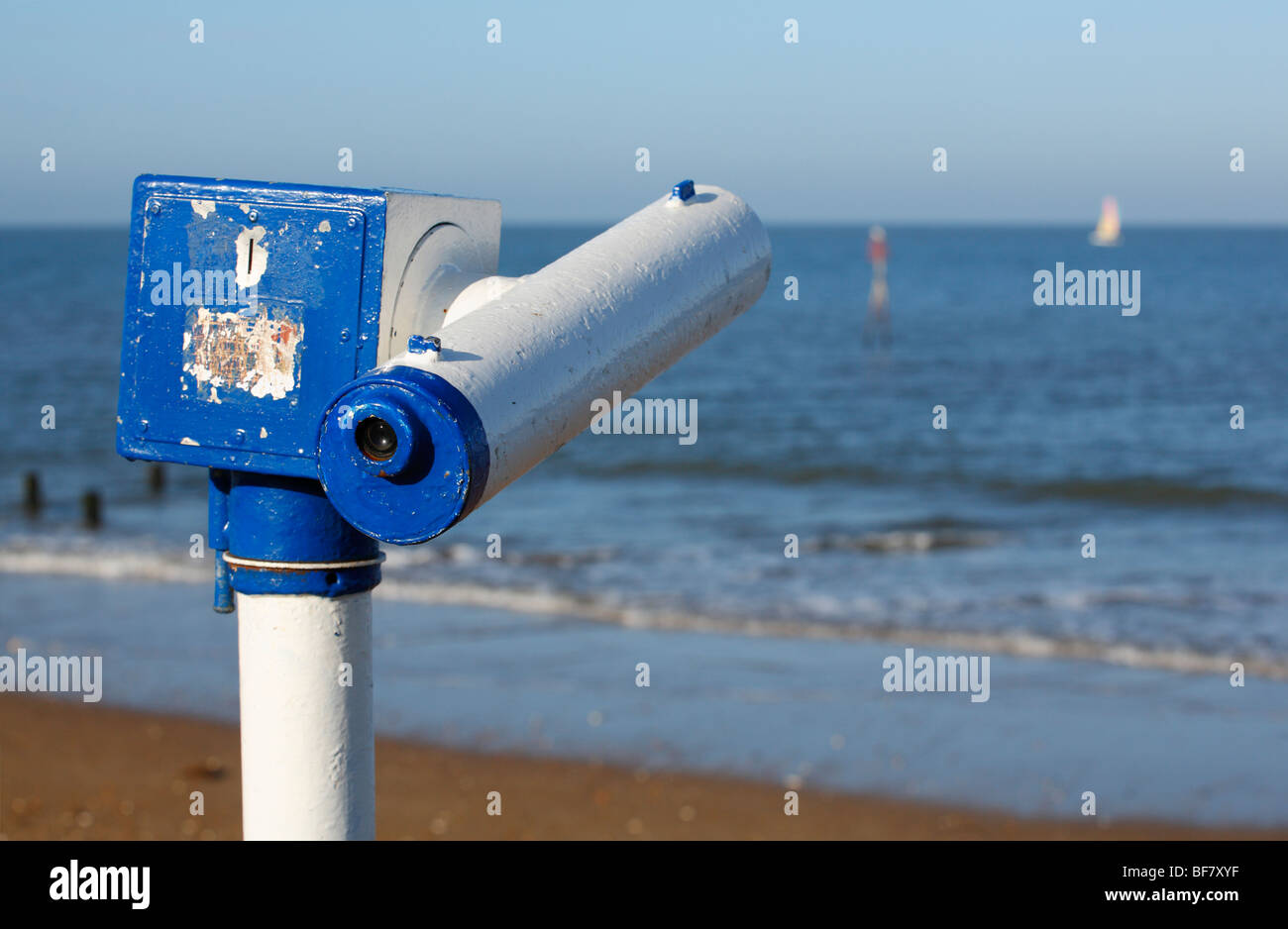 A seaside telescope looking over the sea with a distant sail visible ...