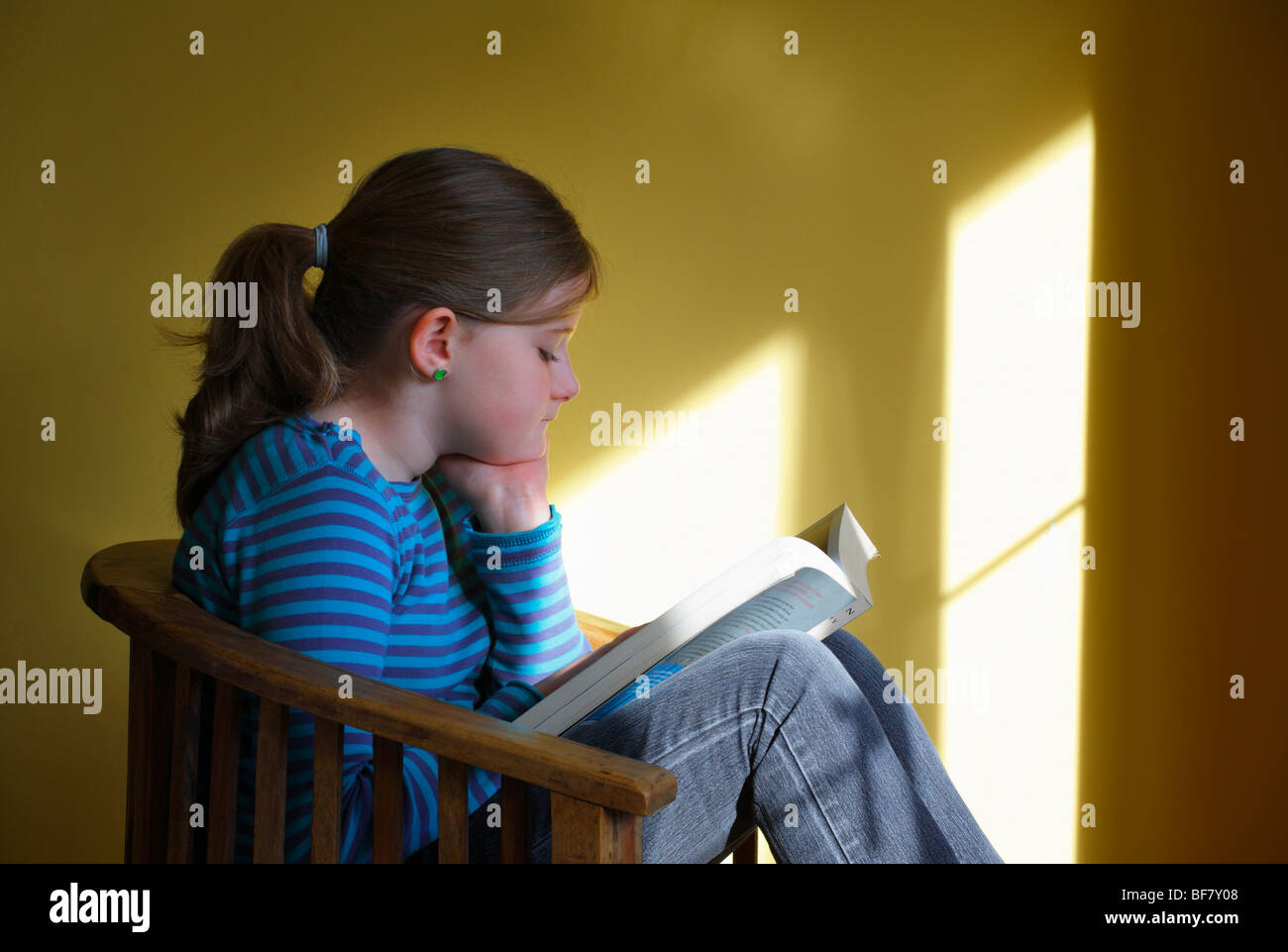 Ten year old girl reading a book by the light from a window Stock Photo ...