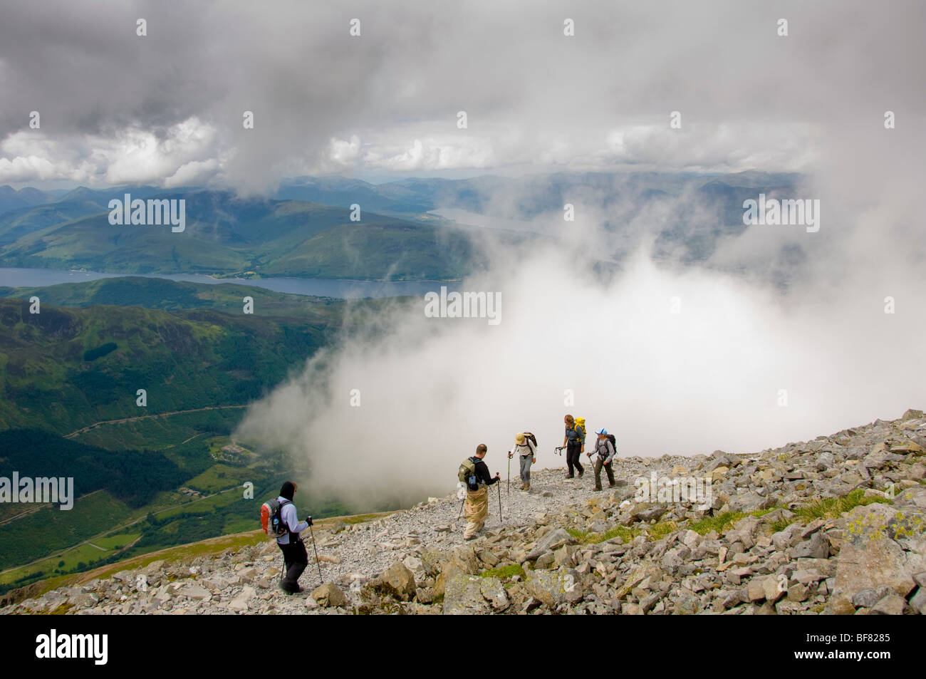 Walkers using trekking poles on the rocky path, above the clouds on Ben ...