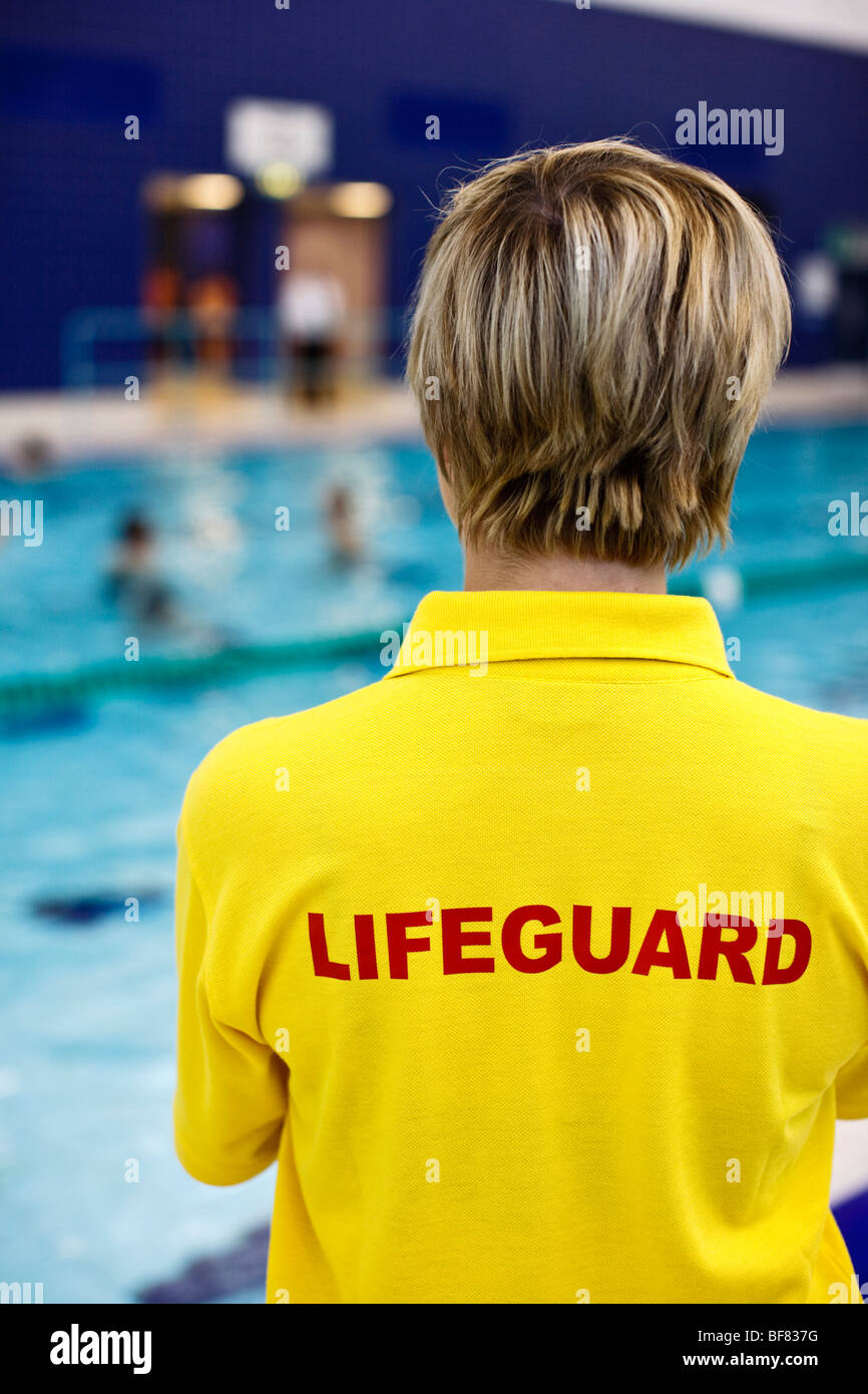 Female lifeguard watching swimmers at an indoor swimming pool in the UK ...