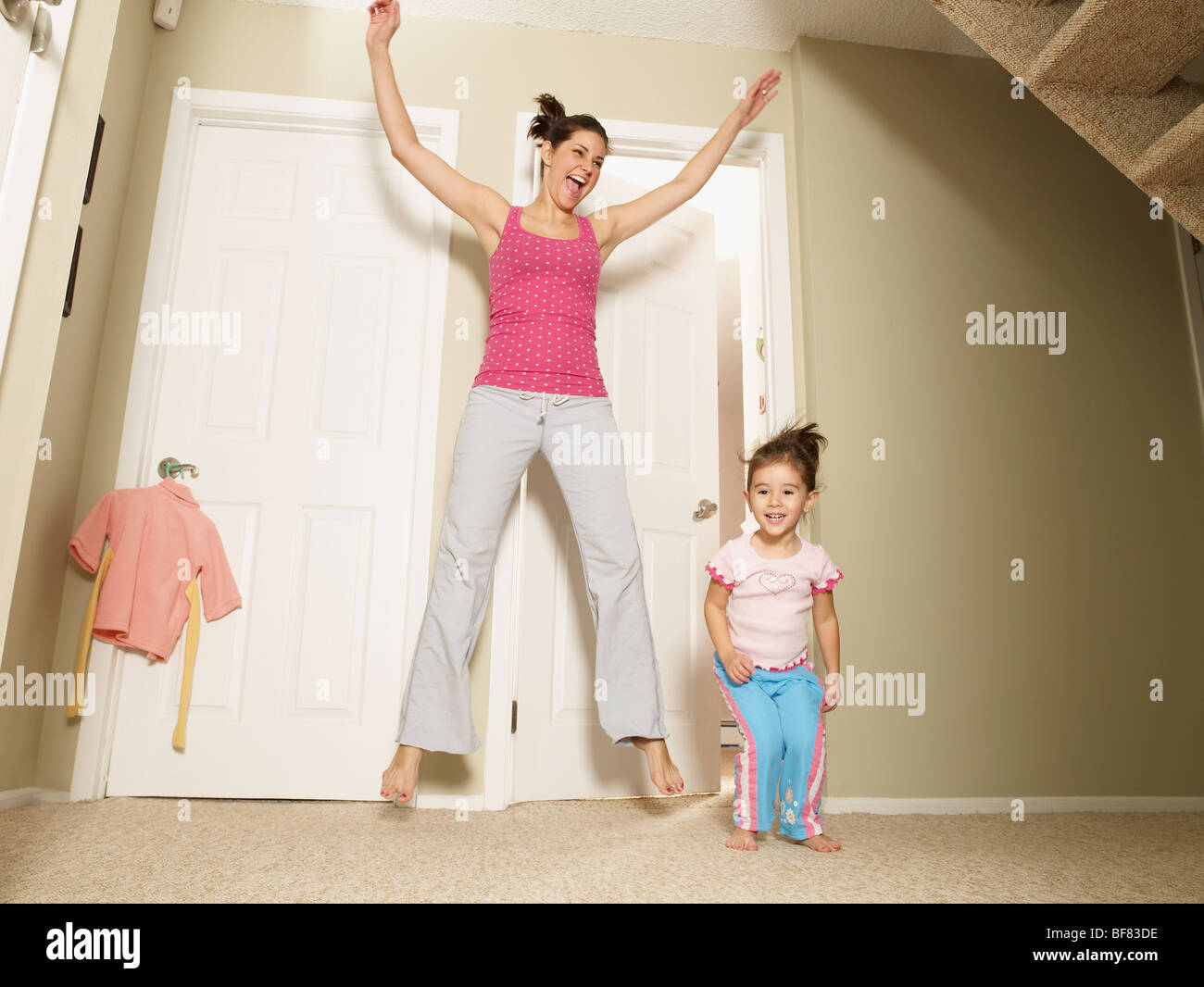 Mother and daughter jumping in house Stock Photo - Alamy