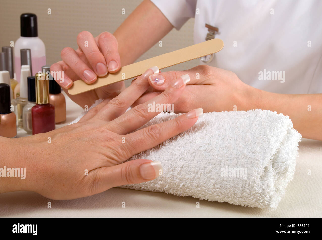 Manicurist filing clients nails Stock Photo - Alamy