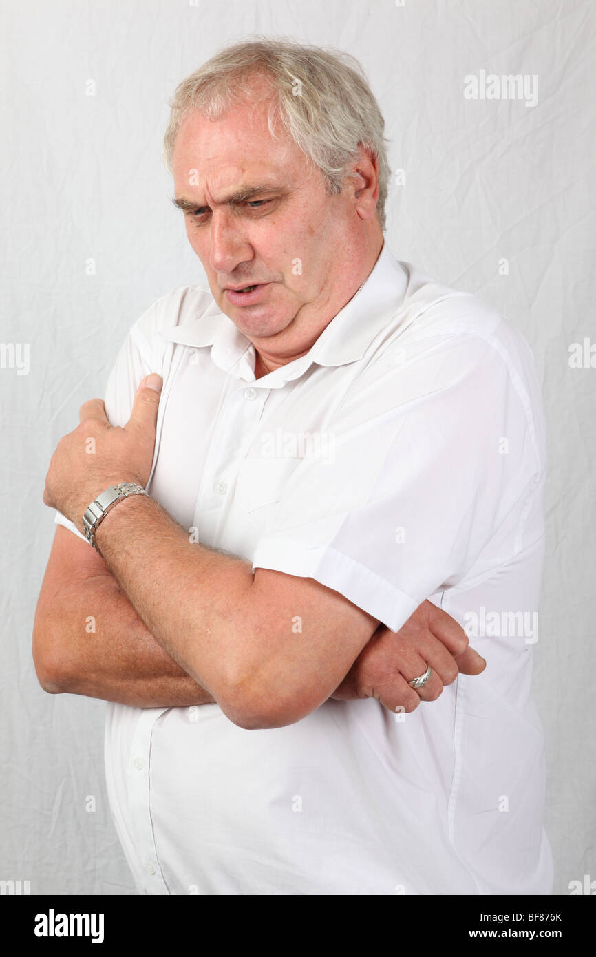 Mid 60s man with arms around upper body shivering from cold sickness ...