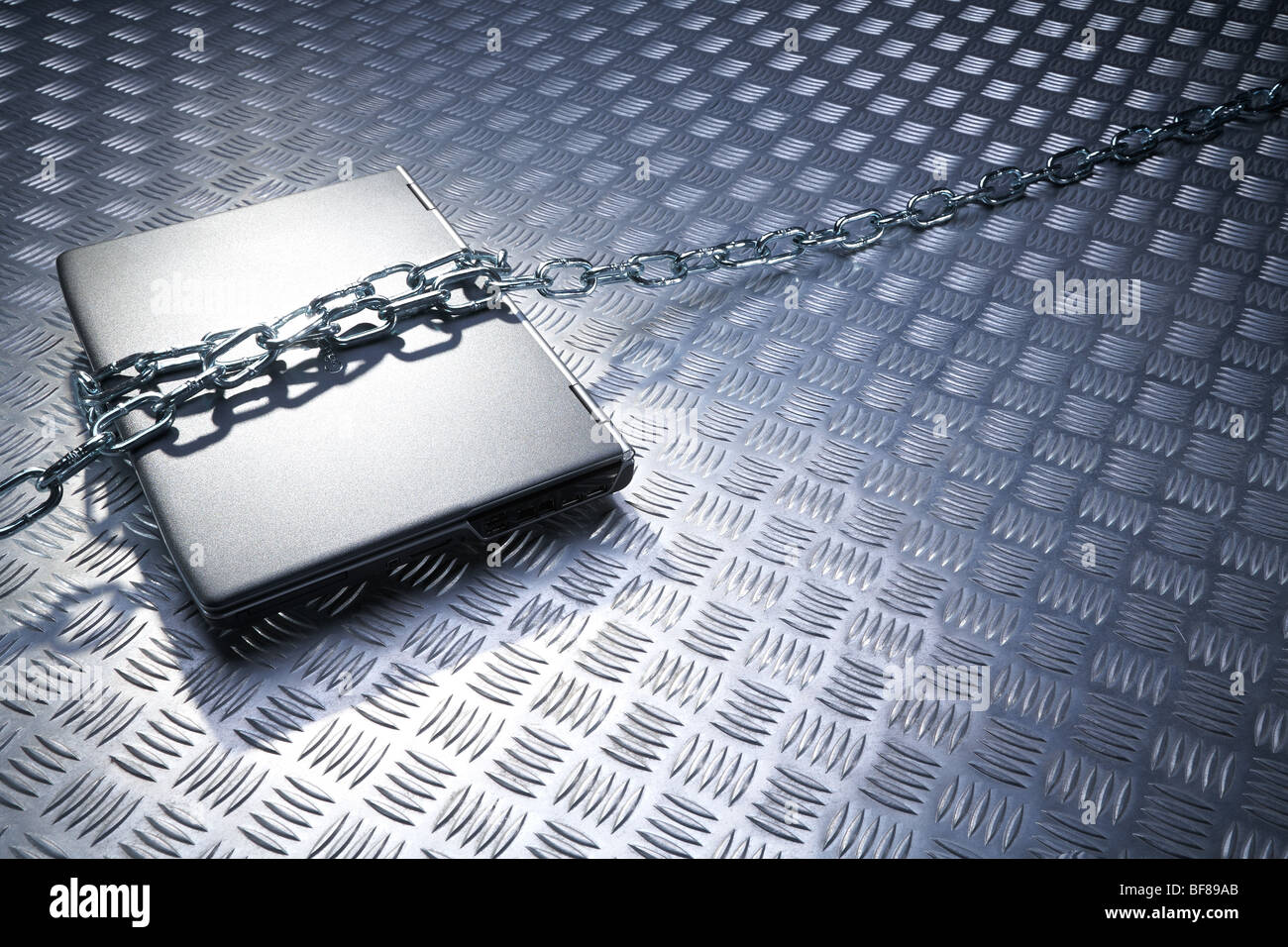 Laptop in chains on metal back ground Stock Photo - Alamy