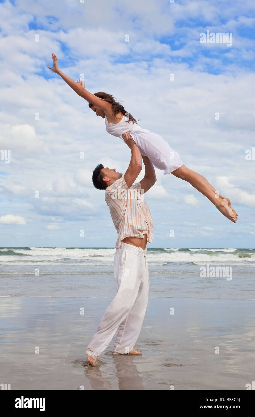 A young man holding his girlfriend above is head as she jumps in ...