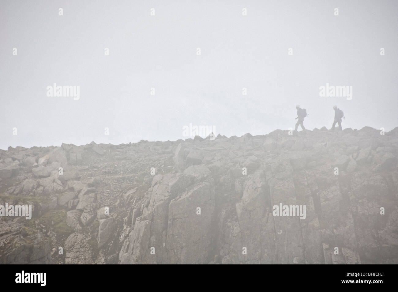Climbers in the mist, on a steep ridge heading toward summit of Ben ...