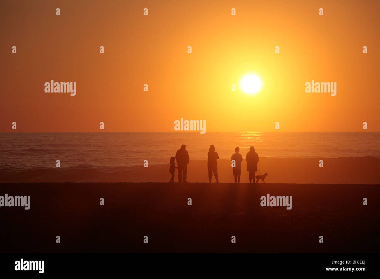 a group of people watch the sun set over the Pacific Ocean California ...
