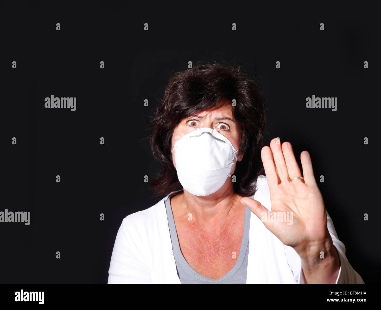 Woman with surgical mask holding up hand to keep the swine flu away ...