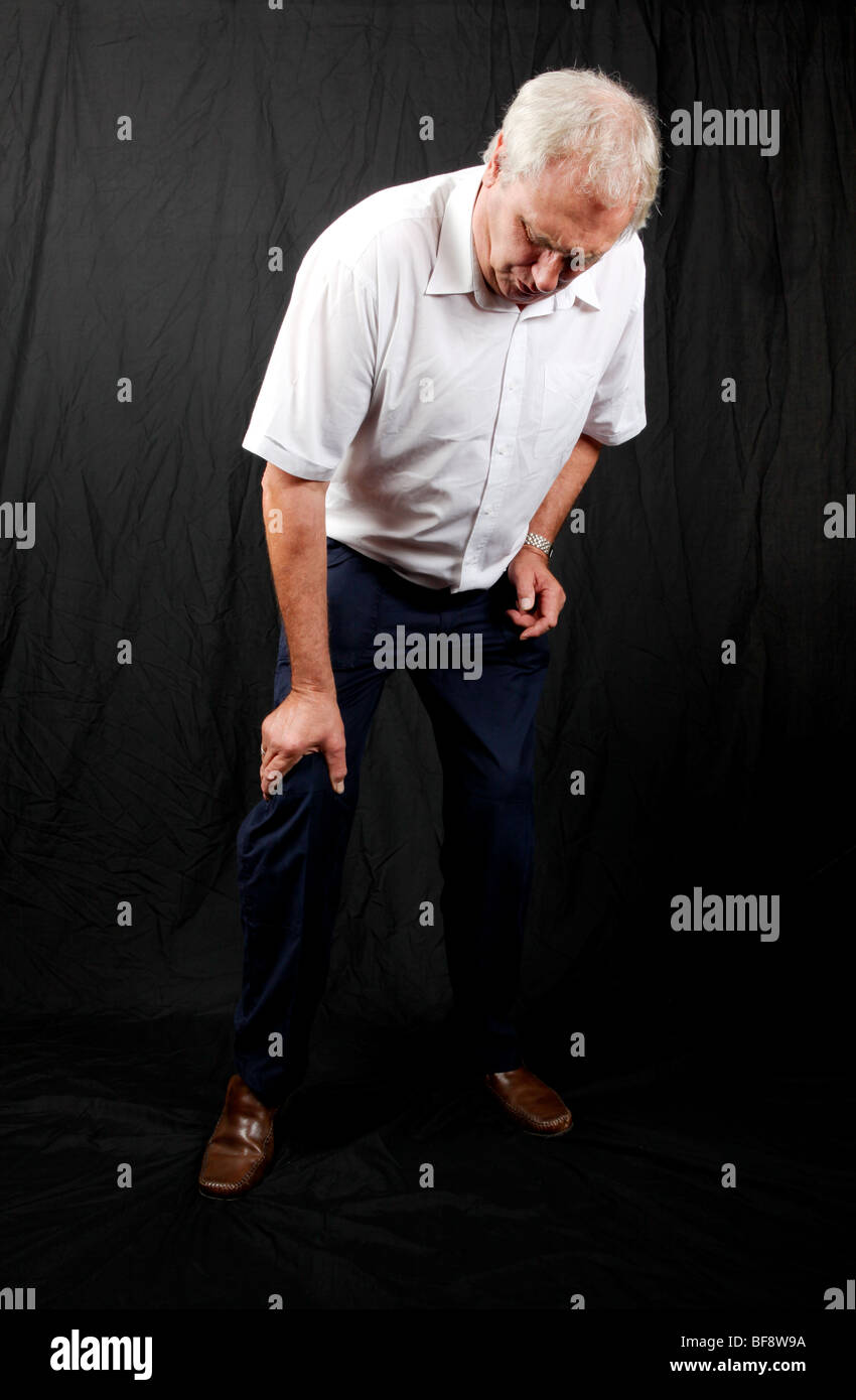 Late middle aged man holding painful knee joint suffering from severe ...