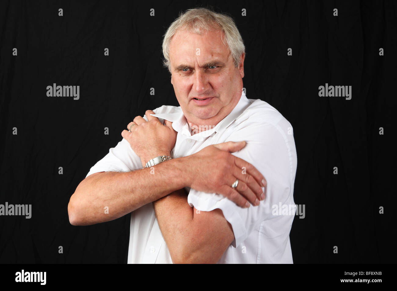 50s 60s man shivering feeling cold holding arms around own body trying ...