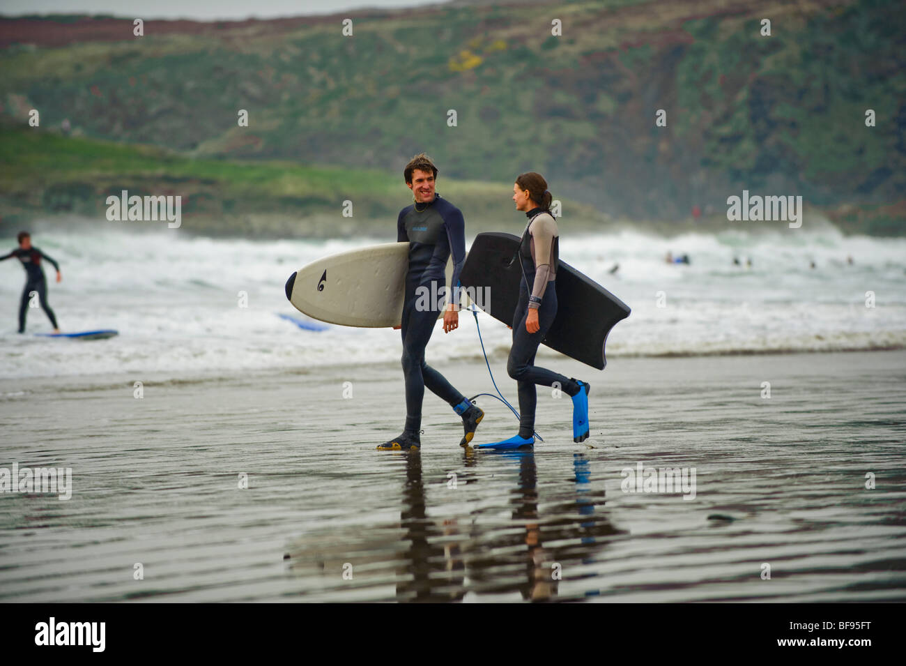 A man and woman going surfing at Whitesands bay, pembrokeshire coast ...