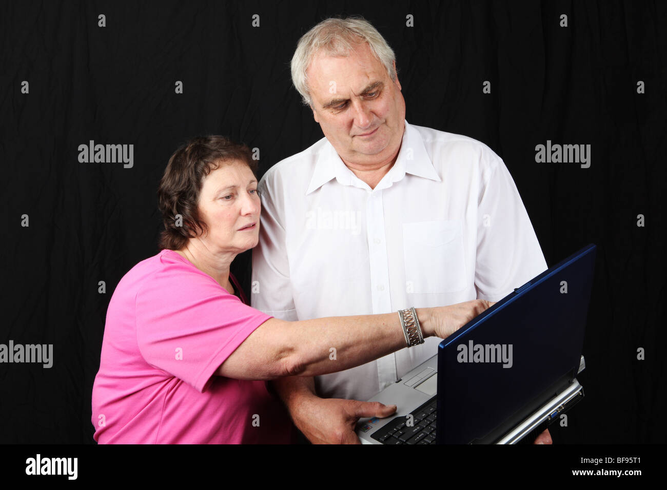 Married couple using wireless laptop silver surfers wife showing ...