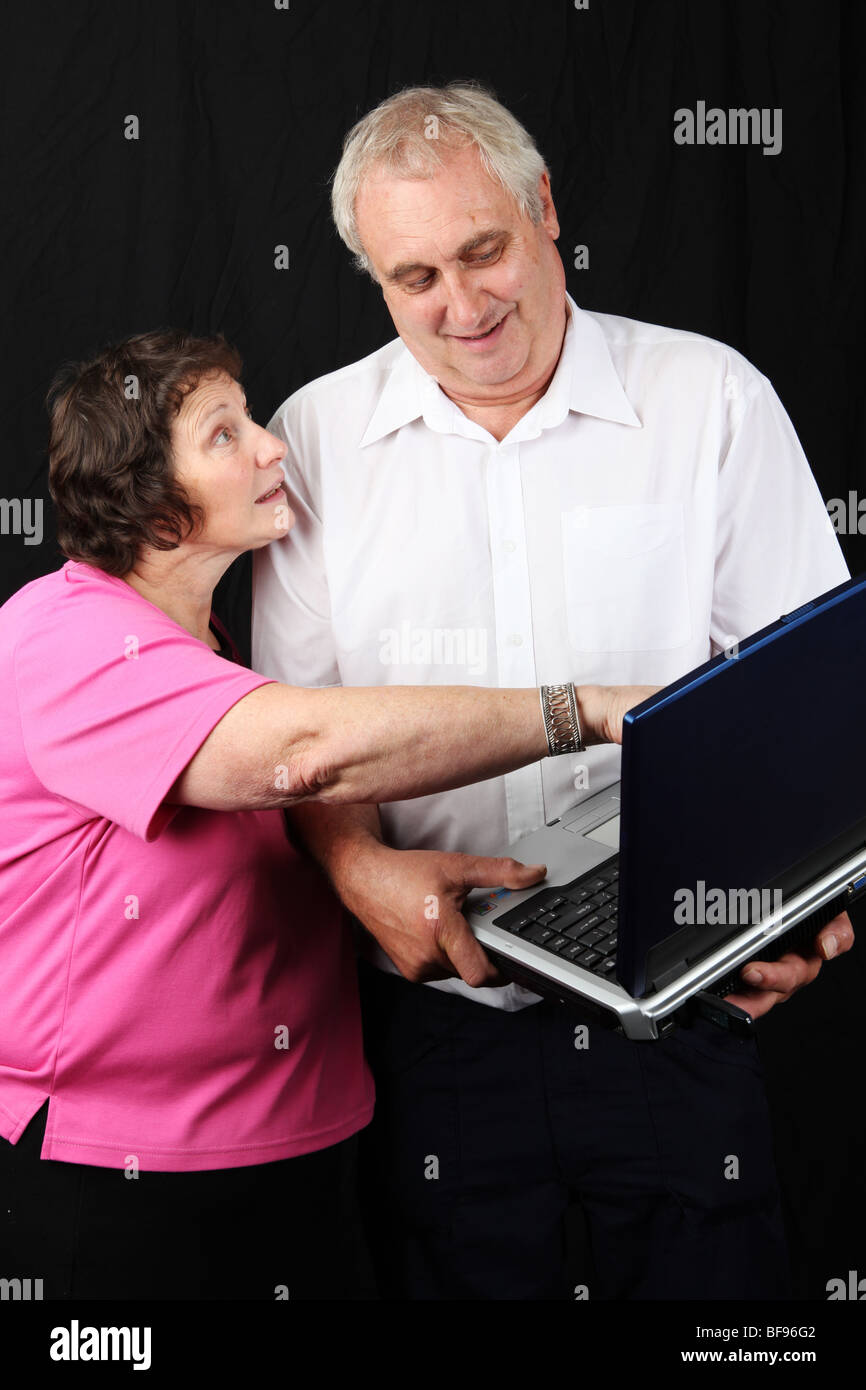 Married couple using wireless laptop silver surfers wife showing ...