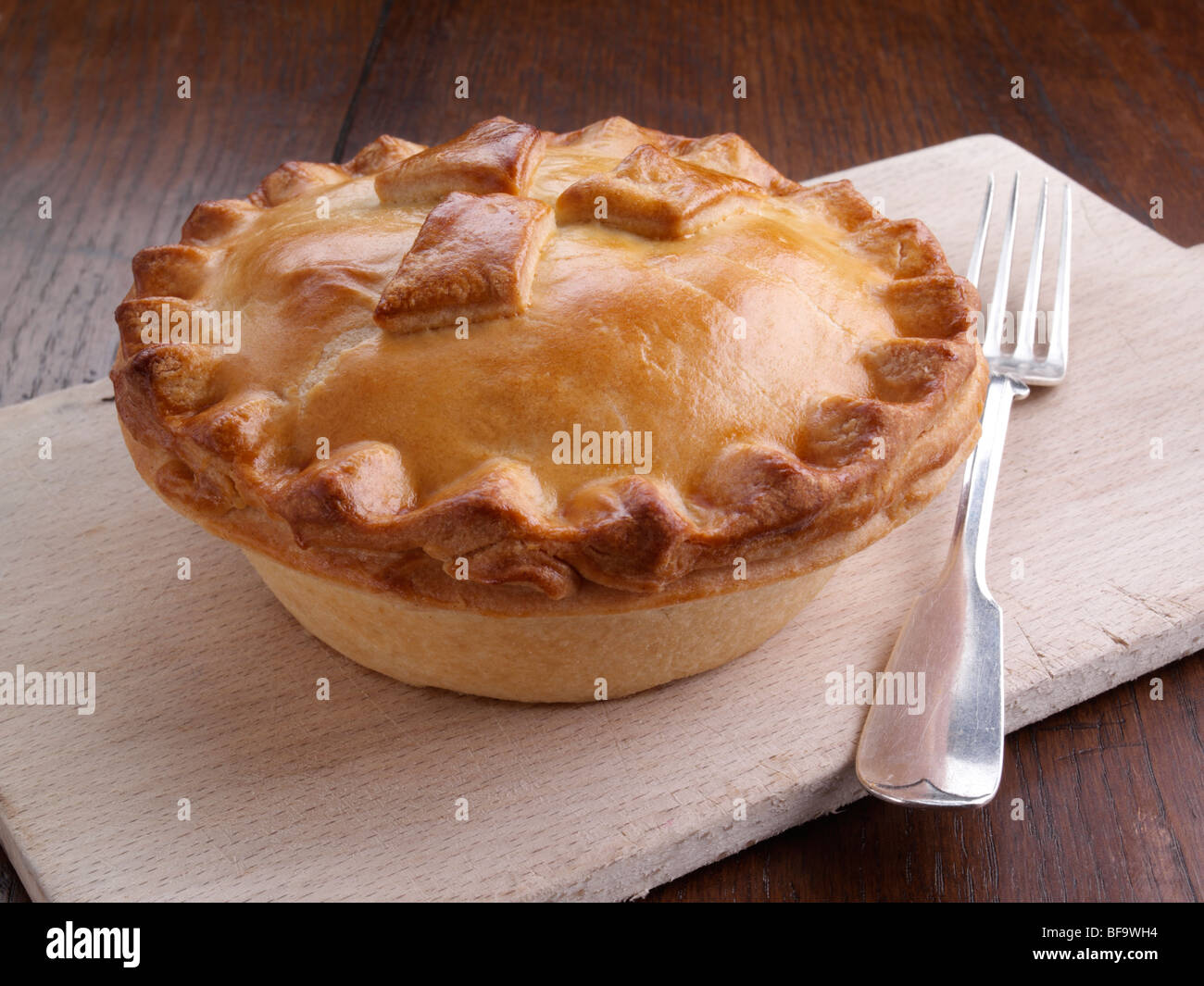 An individual shortcrust pastry pie on a wooden board Stock Photo - Alamy