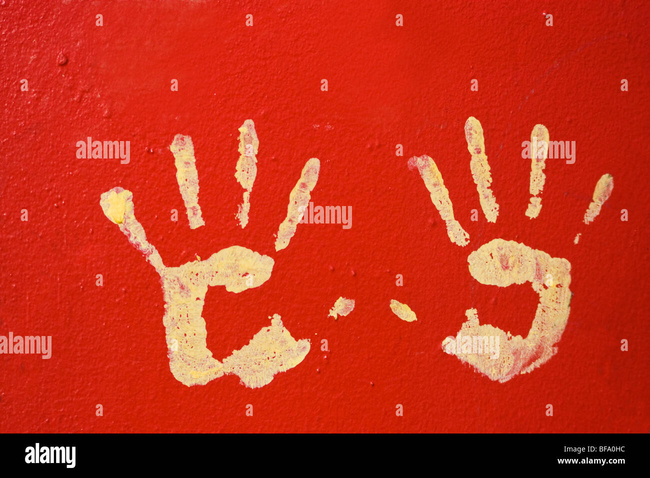 Yellow hands on red wall Stock Photo - Alamy