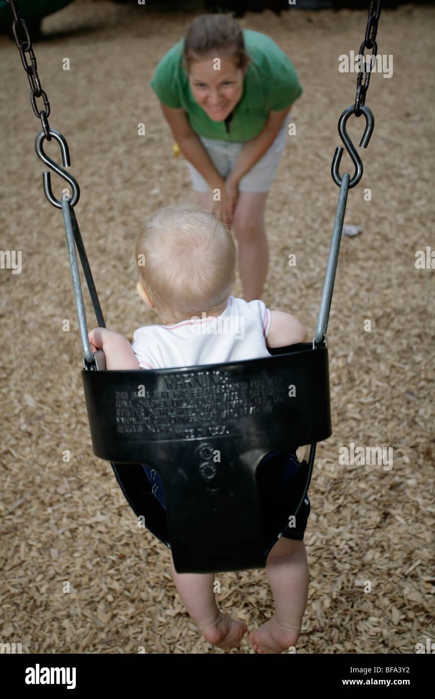 Mom pushing baby boy on a swing and interacting Stock Photo - Alamy