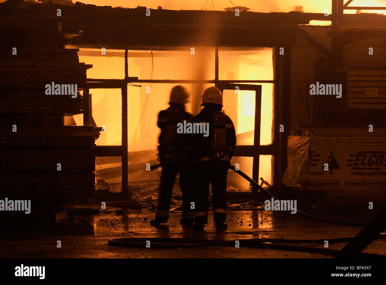 Two firemen in Breathing Apparatus tackle fire at shop at night with ...