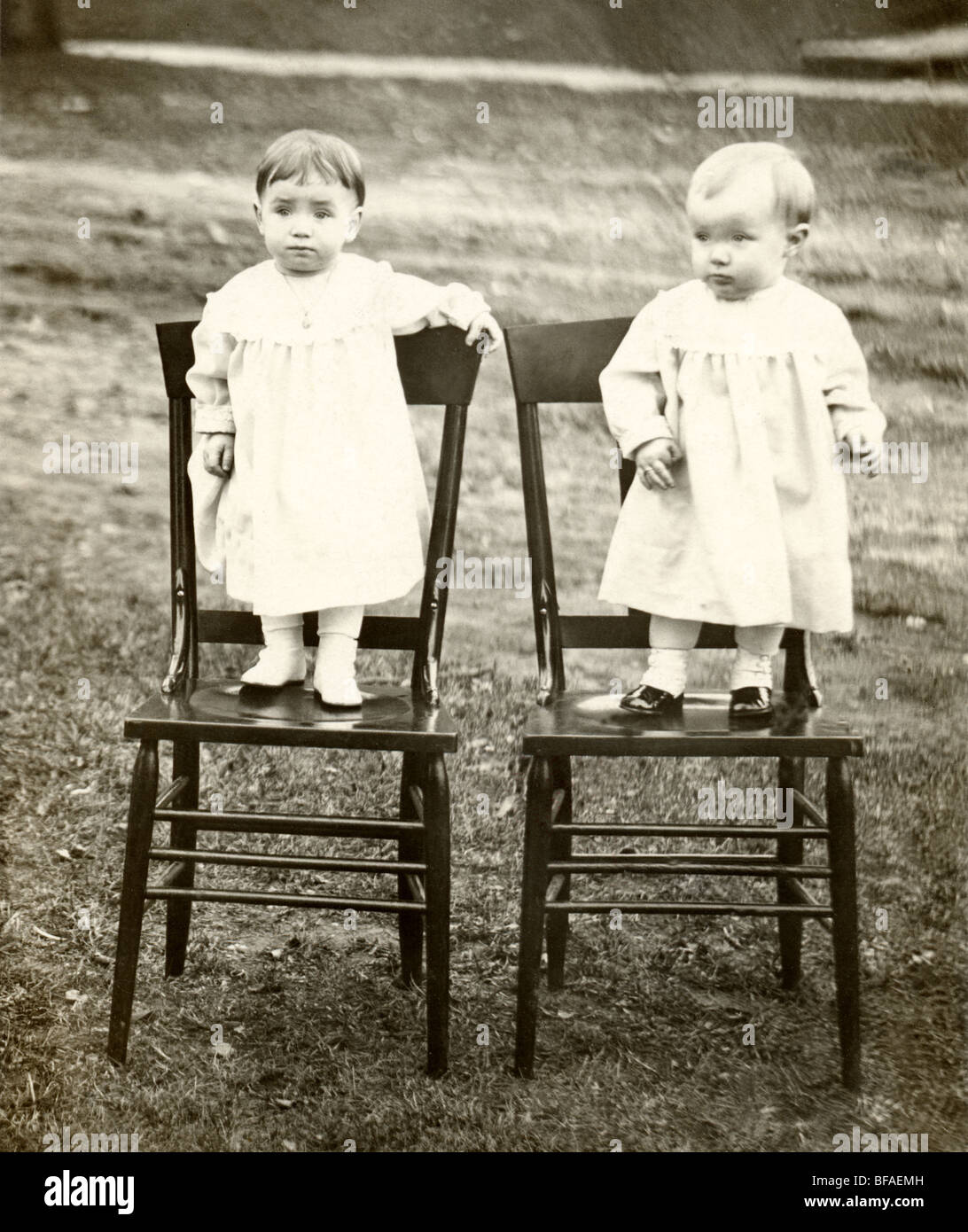 Two Infant Girls Standing on Chairs Outdoors Stock Photo - Alamy