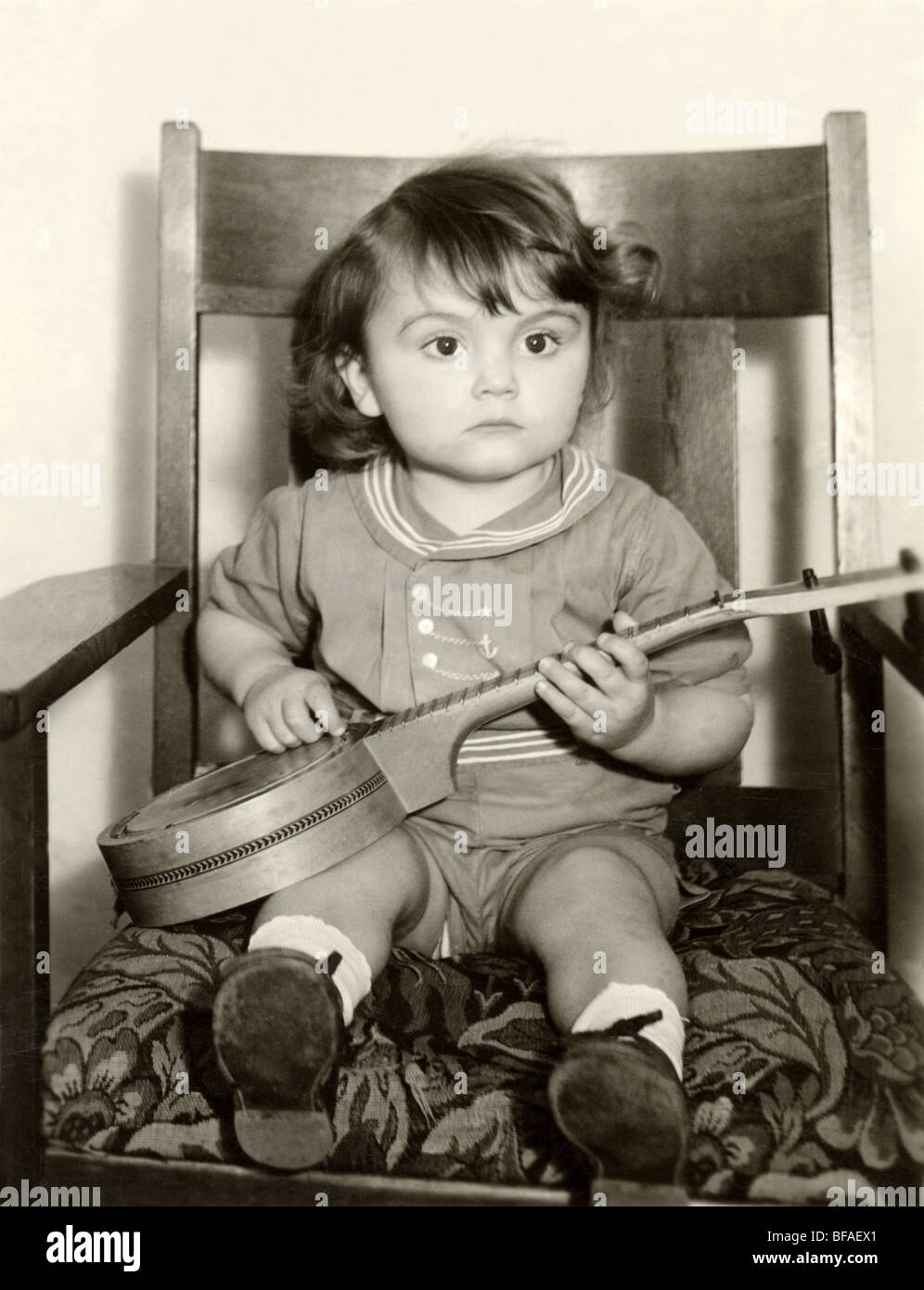 Seated Infant Holding Banjo Stock Photo - Alamy
