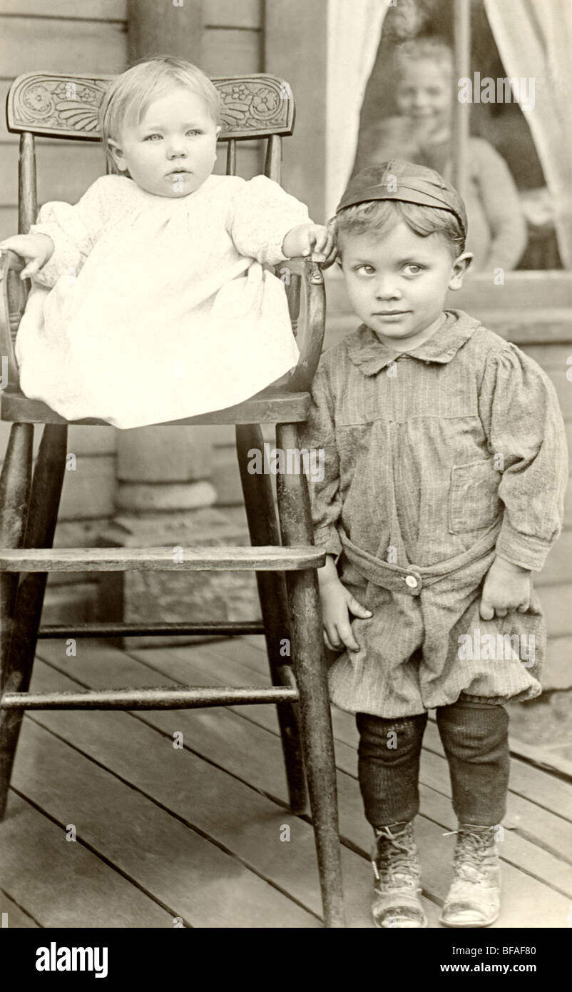 Wary Brother & Infant Sibling in High Chair on Porch Stock Photo - Alamy
