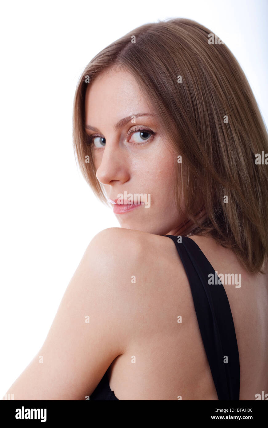 Young woman cautiously looking over her shoulder with a coy expression ...