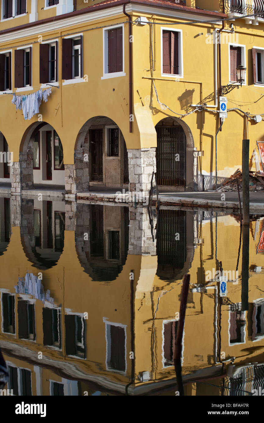 Yellow building reflected in the riva Vena Canal in Chioggia, Venice ...