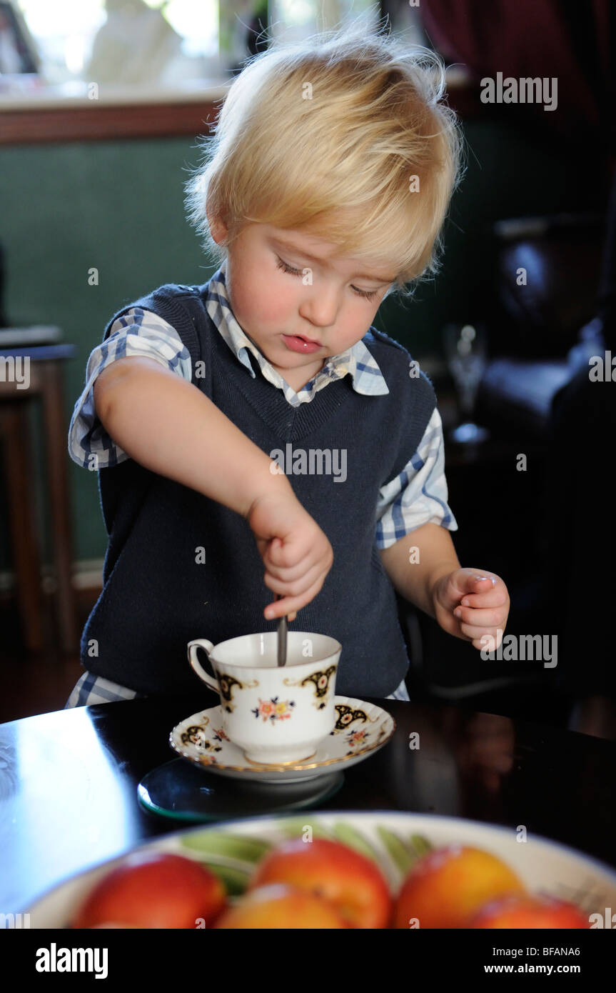 Portrait of a small boy stirring a cup of tea Stock Photo - Alamy