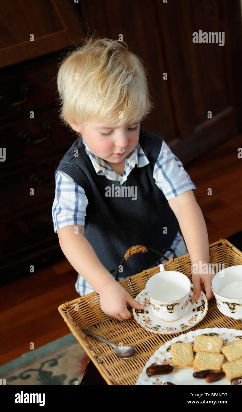 Portrait of a small boy making a cup of tea and using the best bone ...