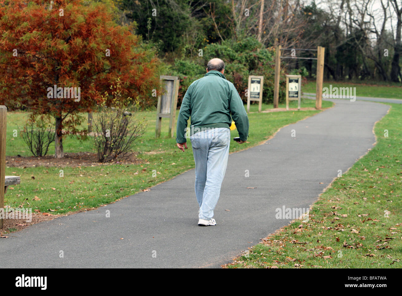 A senior bald headed man walking in the park for exercise. Shot in ...