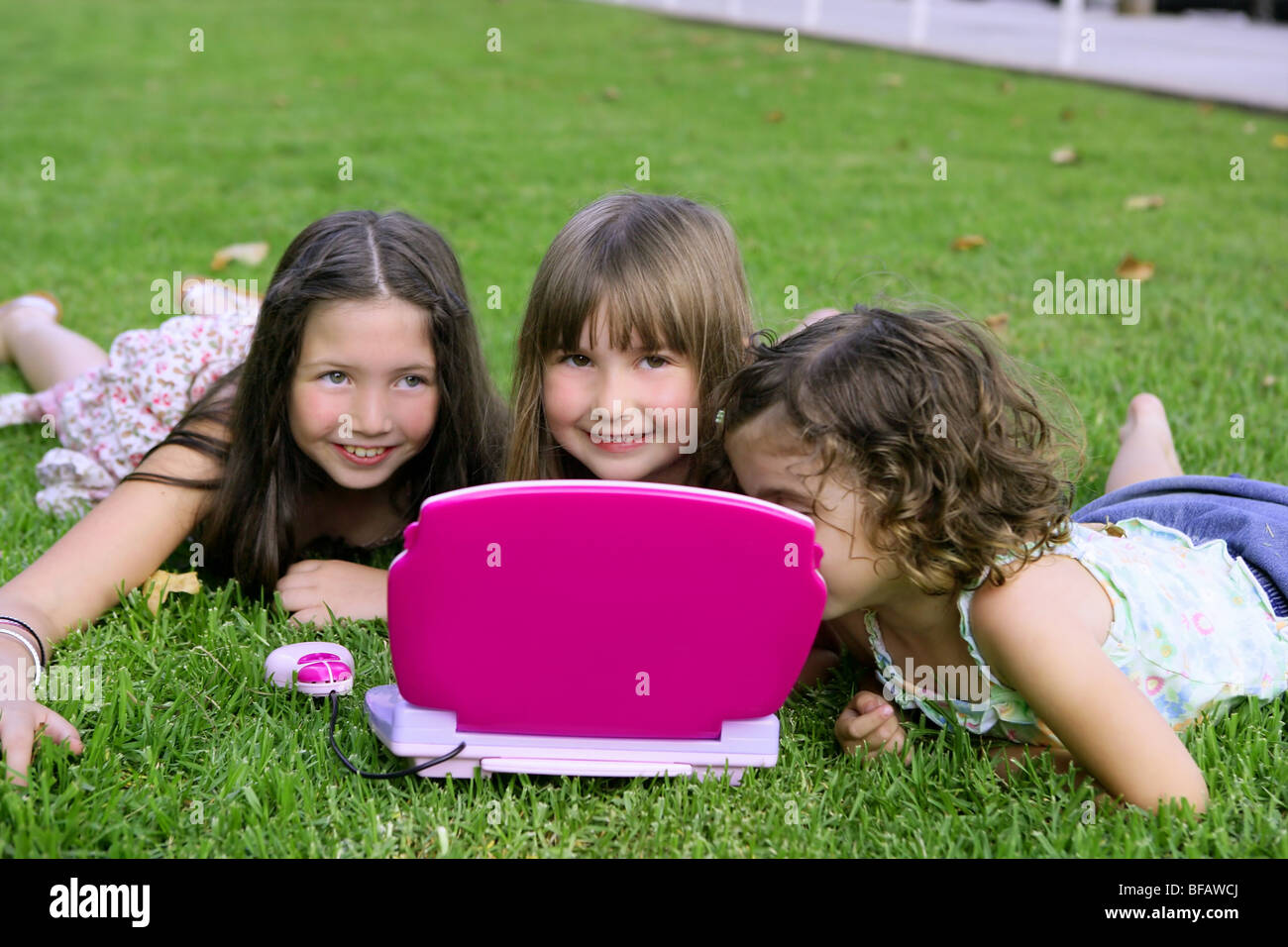 Three little girl outdoor playing with toy computer in grass Stock ...