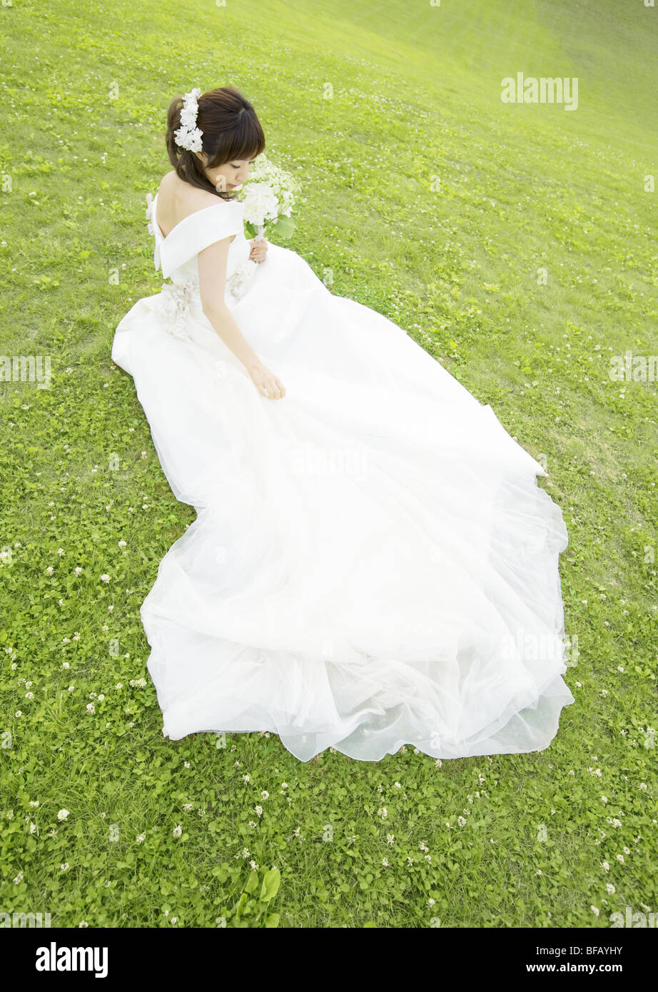 Bride sitting on grass Stock Photo - Alamy