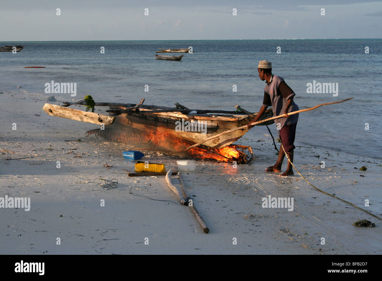 Burning The Seaweed Off The Hull Of A Dhow On Jambiani Beach, Zanzibar ...