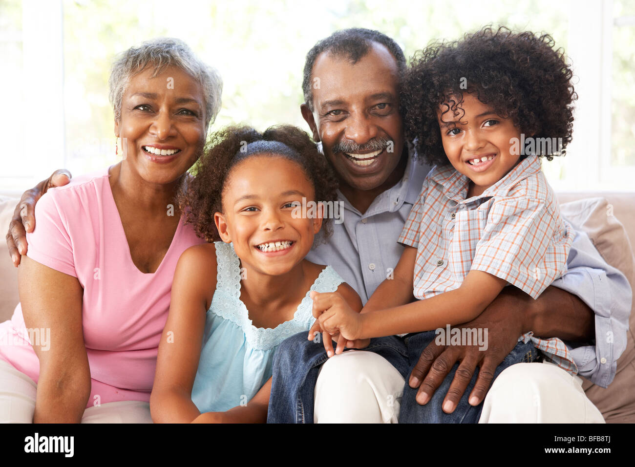 Grandparents With Grandchildren Relaxing On Sofa At Home Together Stock ...