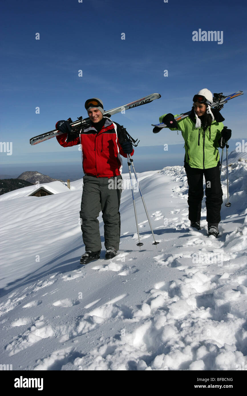 Couple carrying their skis up the mountainside Stock Photo - Alamy