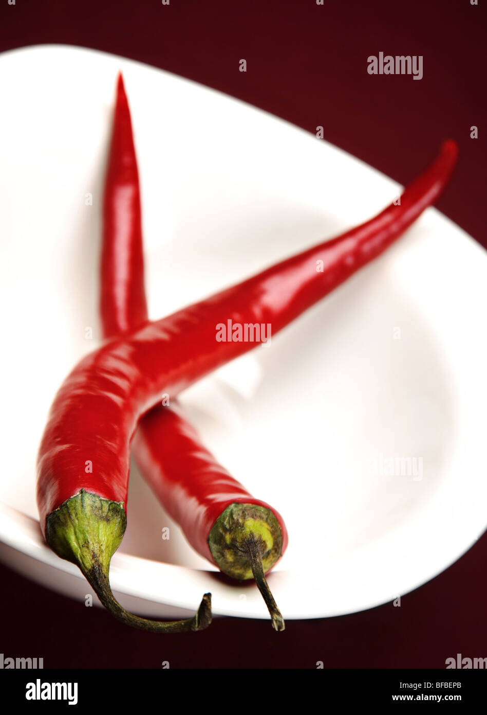 Two red chili pepper in white plate Stock Photo - Alamy