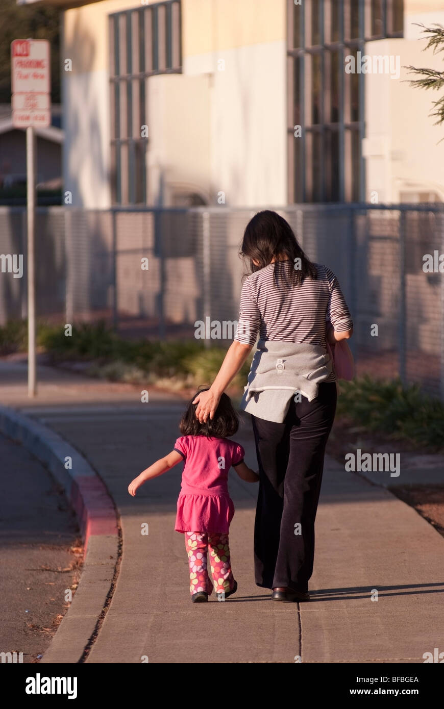 Mother and young child walking down the sidewalk near a neighborhood ...