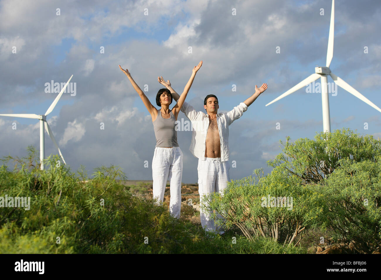 Man and woman stretching near wind turbines Stock Photo - Alamy