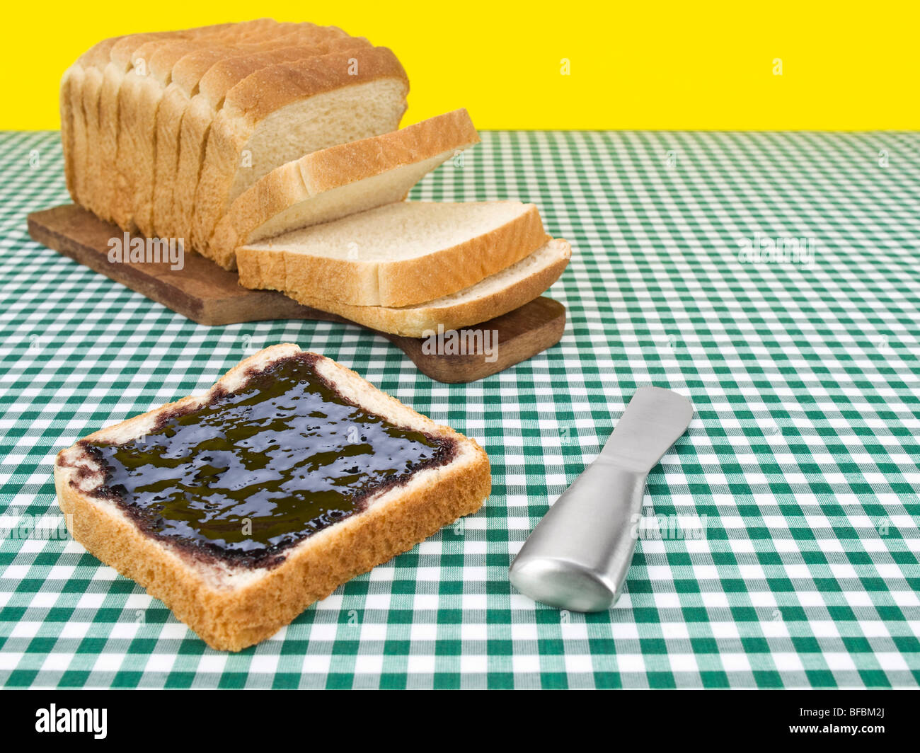 A slice of bread spread with jam beside the loaf of bread Stock Photo ...