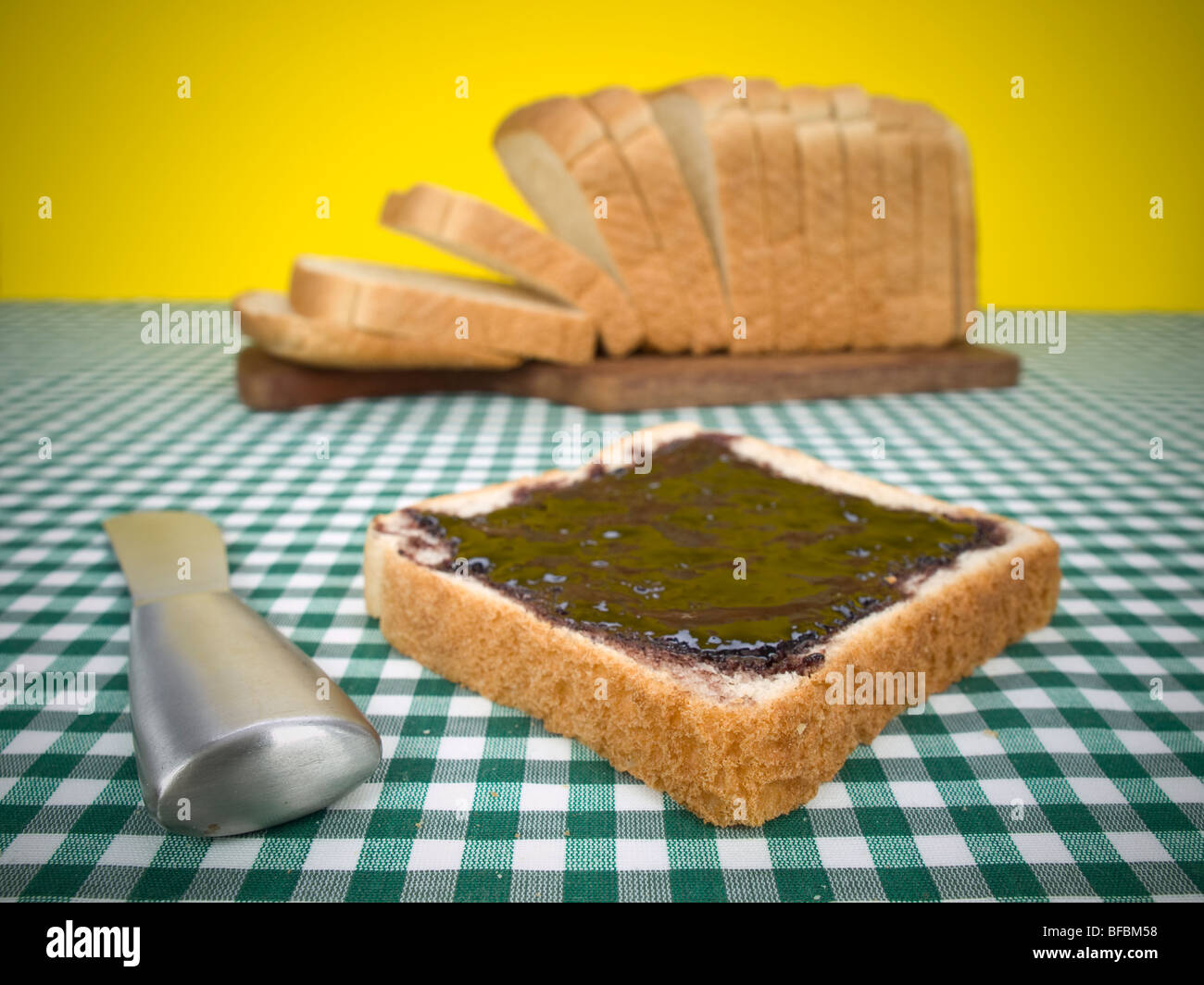 A slice of bread spread with jam. Loaf of bread on the background Stock ...