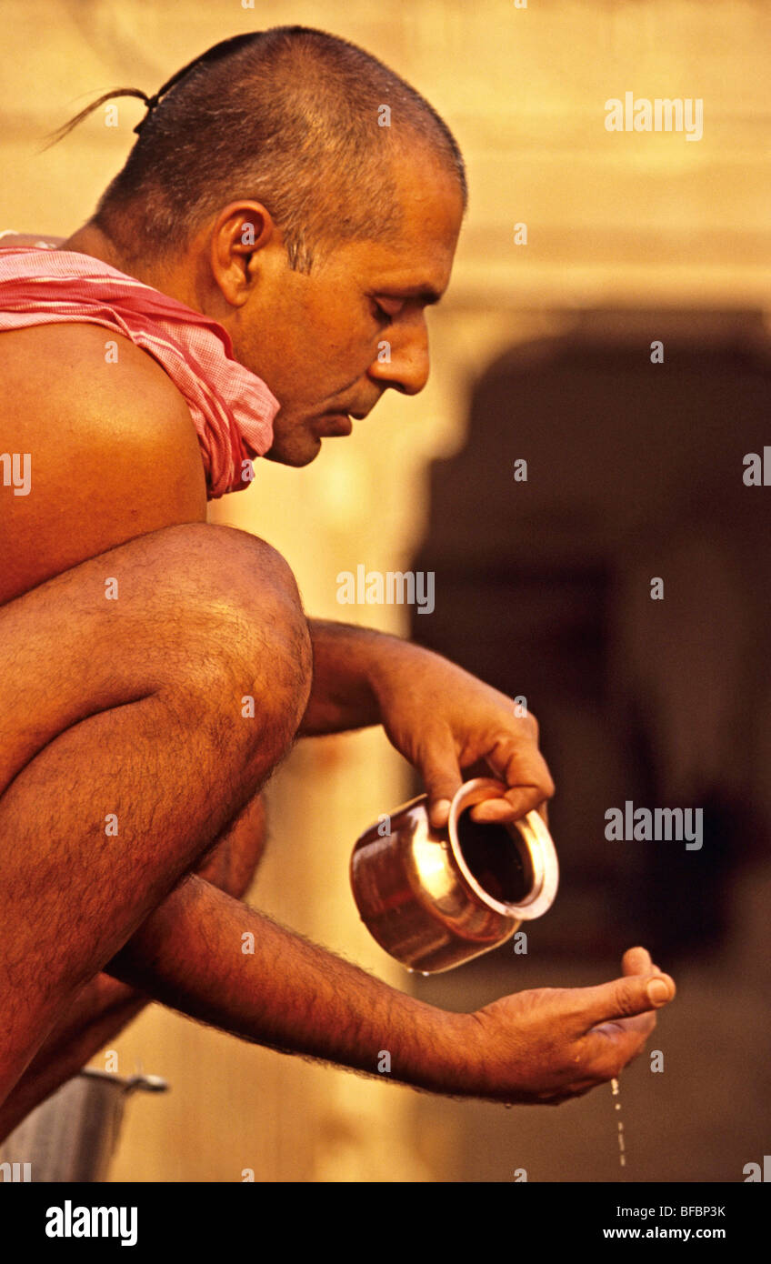 This devotee takes holy water from the Ganges and pours it back into ...