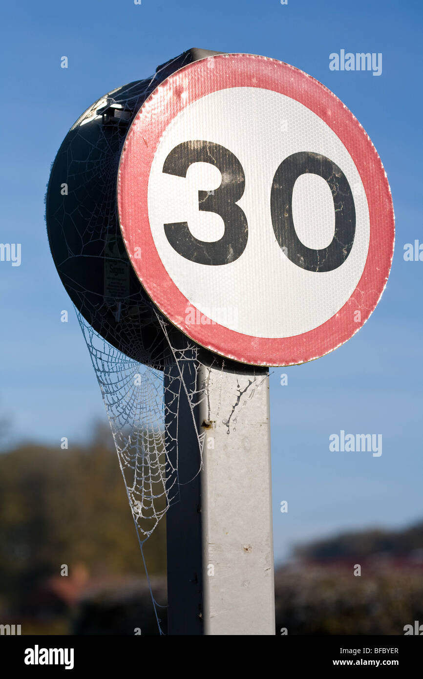 A 30mph speed limit sign in winter, blue sky, spider web with frost ...