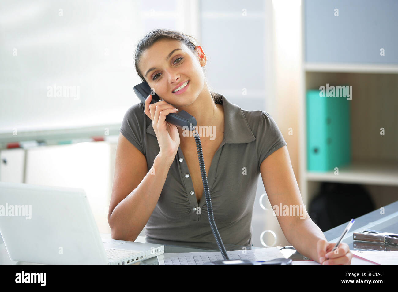 Young woman on the phone at her desk Stock Photo - Alamy