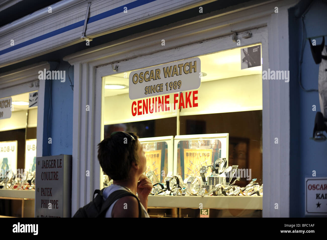 Woman looks through the window of a shop selling fake watches in the ...